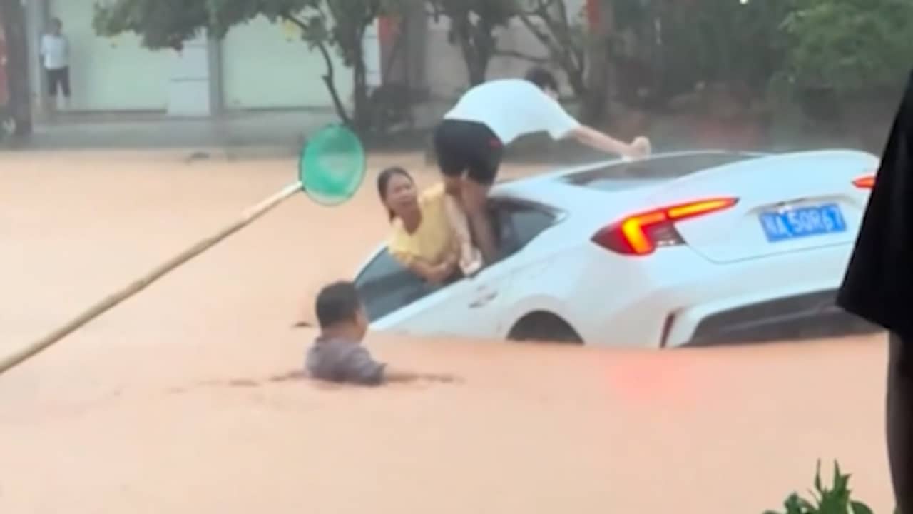 Omstanders redden mensen uit drijvende auto bij overstroming in China ...