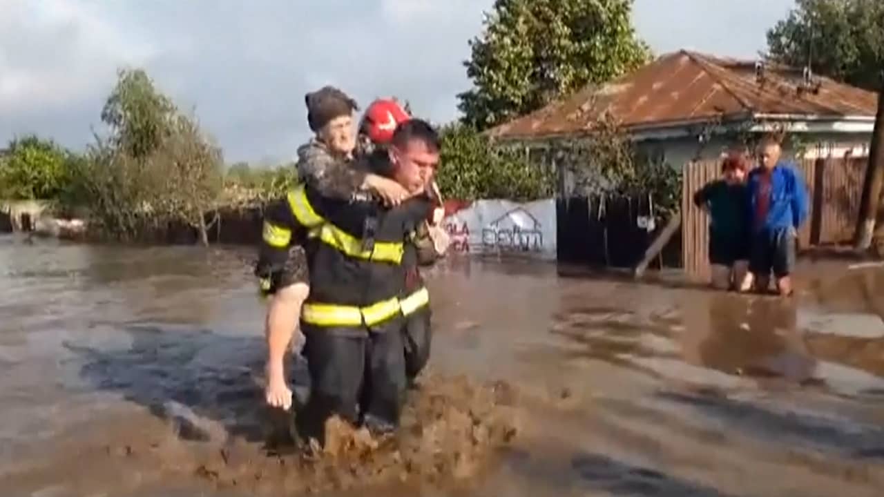 Brandweer draagt Roemenen op rug uit overstroomde huizen | NU.nl