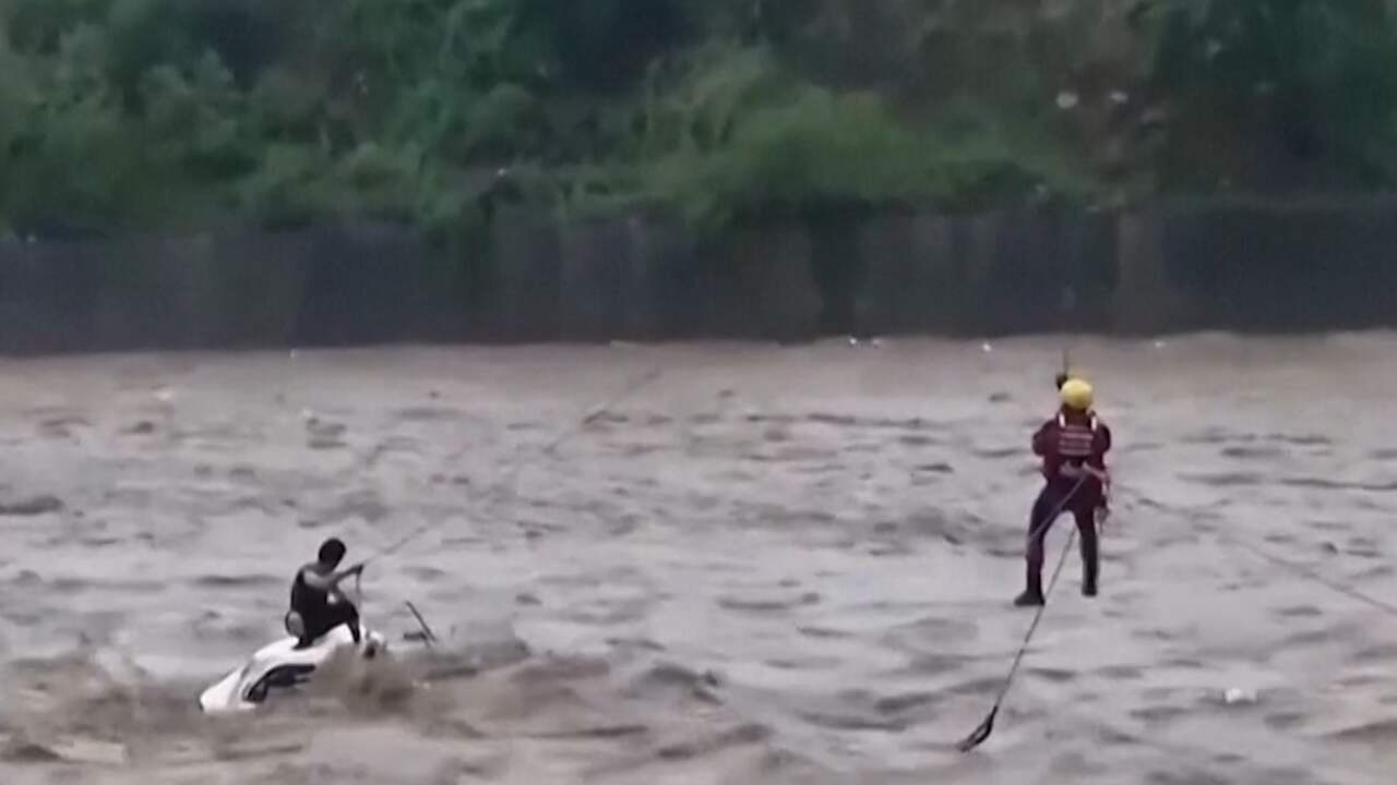 Chinees wordt van zinkende auto in kolkende rivier gered | NU.nl